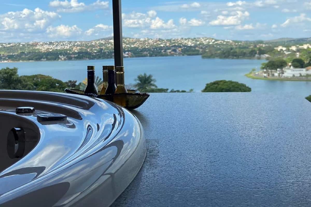 Uma casa de banho moderna com uma grande janela com vista para um lago e para a paisagem urbana.