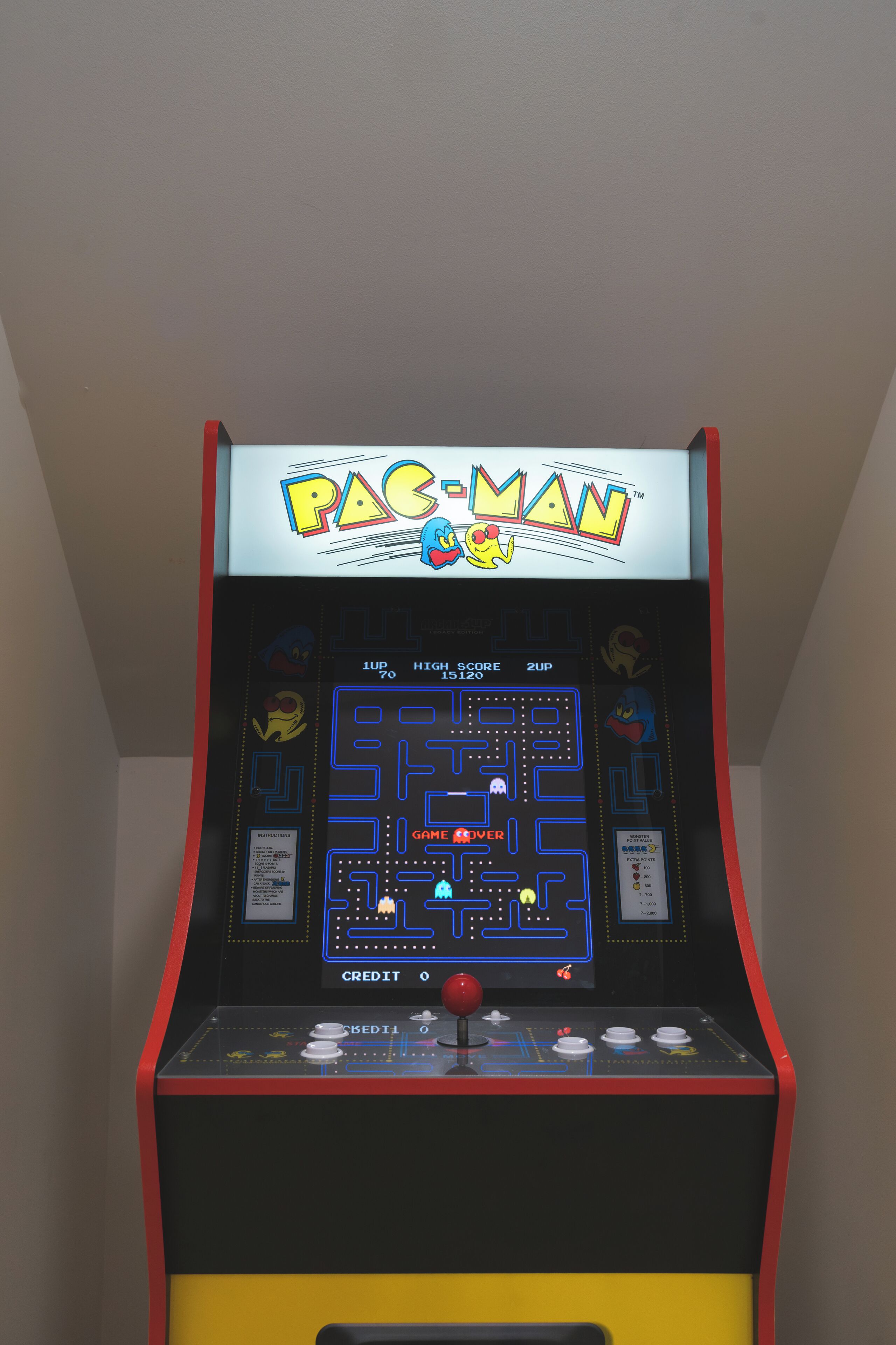 Máquina de jogos de arcade Pac-Man com um jogo de labirinto exibido na tela.