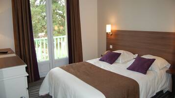 Quarto de hotel com cama, mesa de cabeceira, luminária e vista para o exterior pela janela.