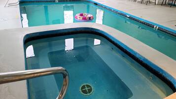 Piscina interior com trampolim, espreguiçadeiras e área ao redor da piscina.