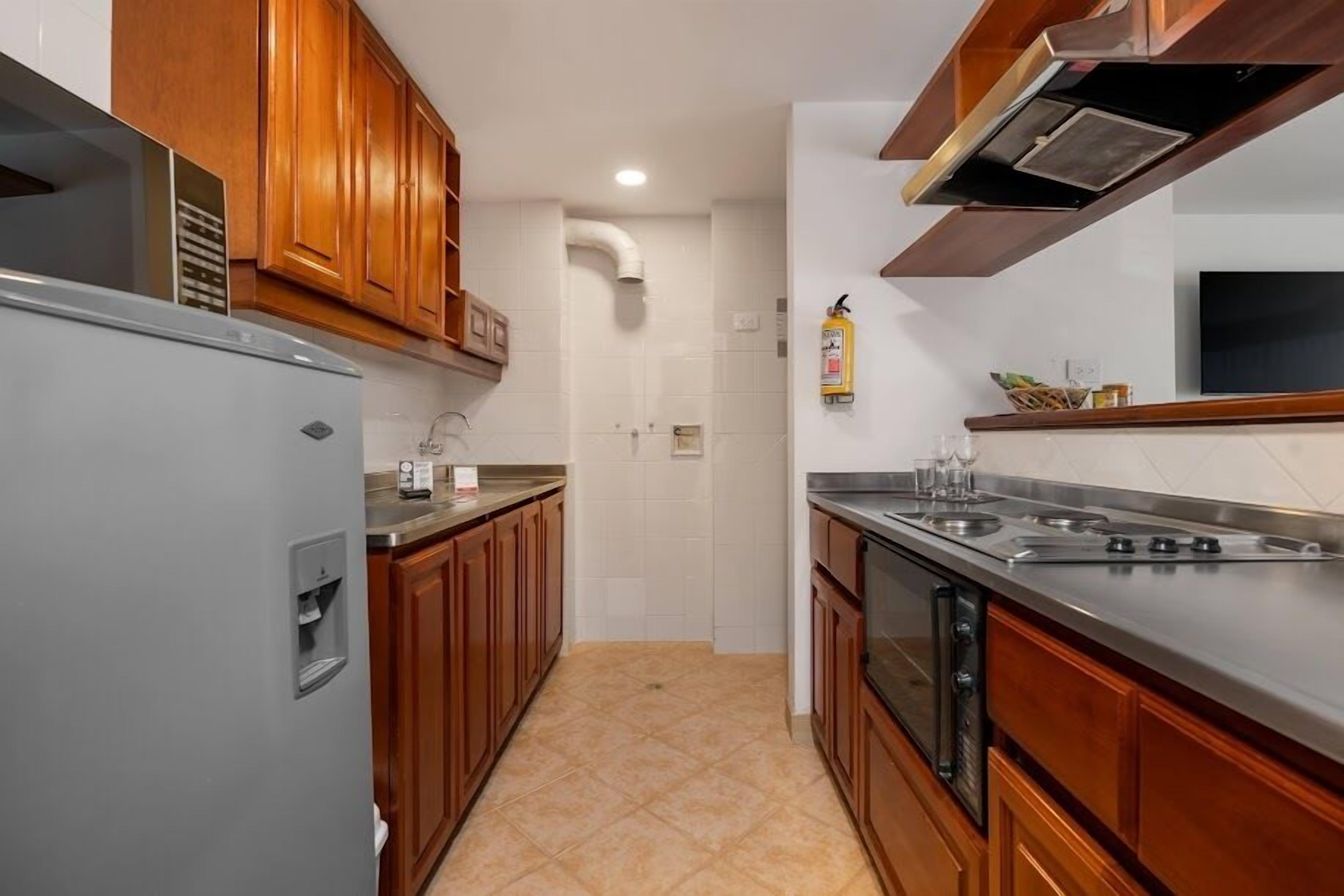 Uma cozinha com armários de madeira, bancada de aço inoxidável, forno embutido e um dispensador de água.