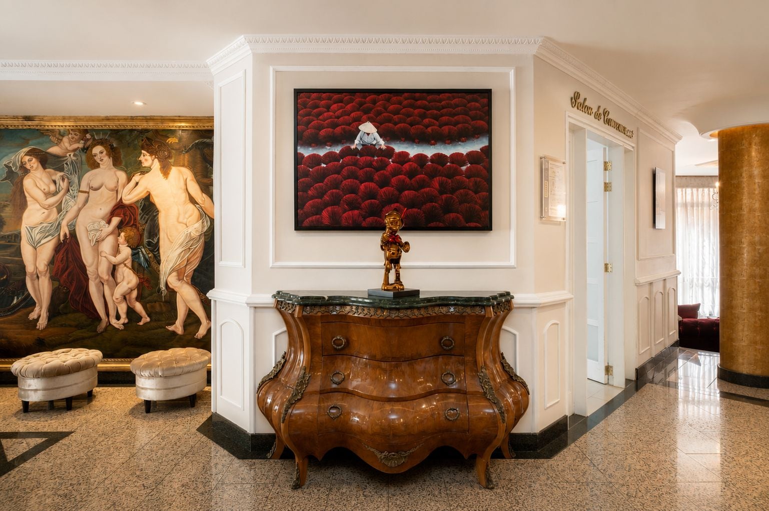 Um hall de entrada luxuoso, com um quadro clássico, uma obra de arte moderna e um imponente console de madeira.