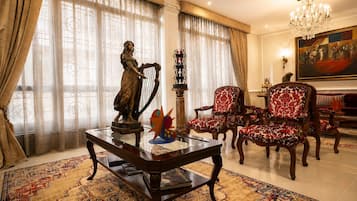 Um salão imponente com uma estátua de harpa, cadeiras ornamentadas e um lustre.