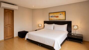 Quarto com cama, mesas de cabeceira, ar-condicionado e um quadro na parede.
