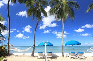 Na praia, espreguiçadeiras, guarda-sóis, toalhas de praia 