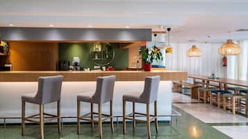 Uma área de bar moderna com balcão, banquetas e uma mesa de jantar com bancos.
