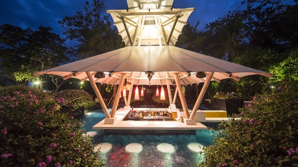 Uma área de bar à beira da piscina, com toldo e piscina.