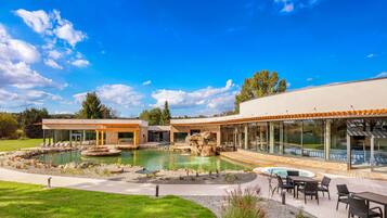 Um resort moderno com piscina, área de estar externa e espaço para spa com paredes de vidro.