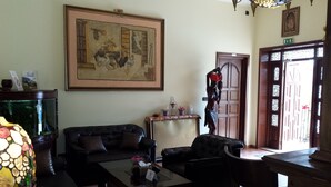 Uma sala de estar com uma grande obra de arte emoldurada, um aquário, um sofá, uma mesa de centro e uma estátua.