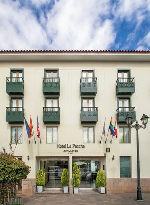 Um hotel com fachada plana, várias varandas e bandeiras.