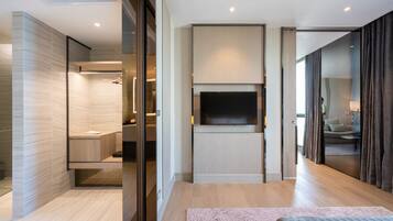 Quarto de hotel moderno com televisão de tela plana na parede, piso de madeira e porta de vidro deslizante para uma varanda.