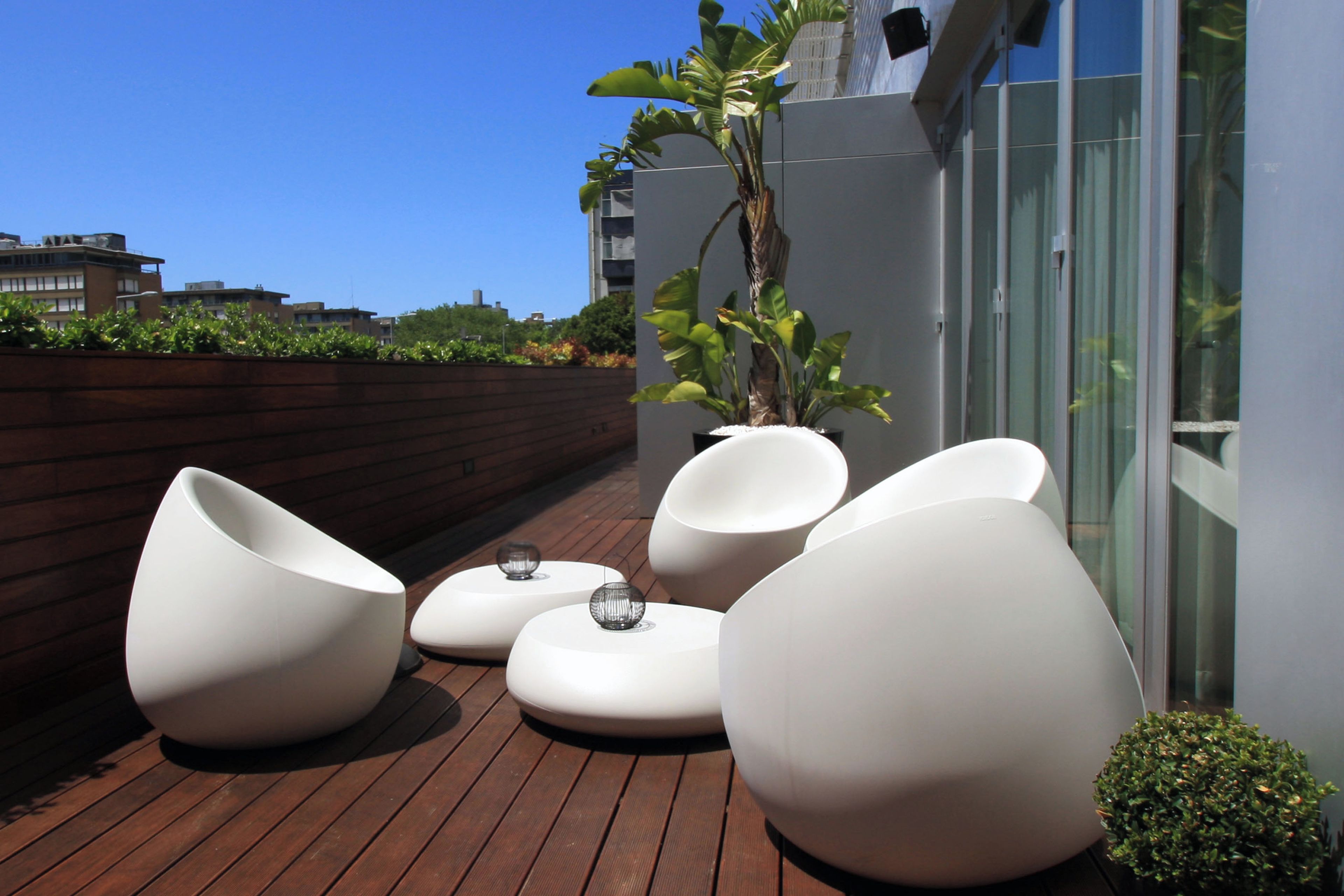 Terraço no telhado com assentos brancos modernos e um vaso de planta.