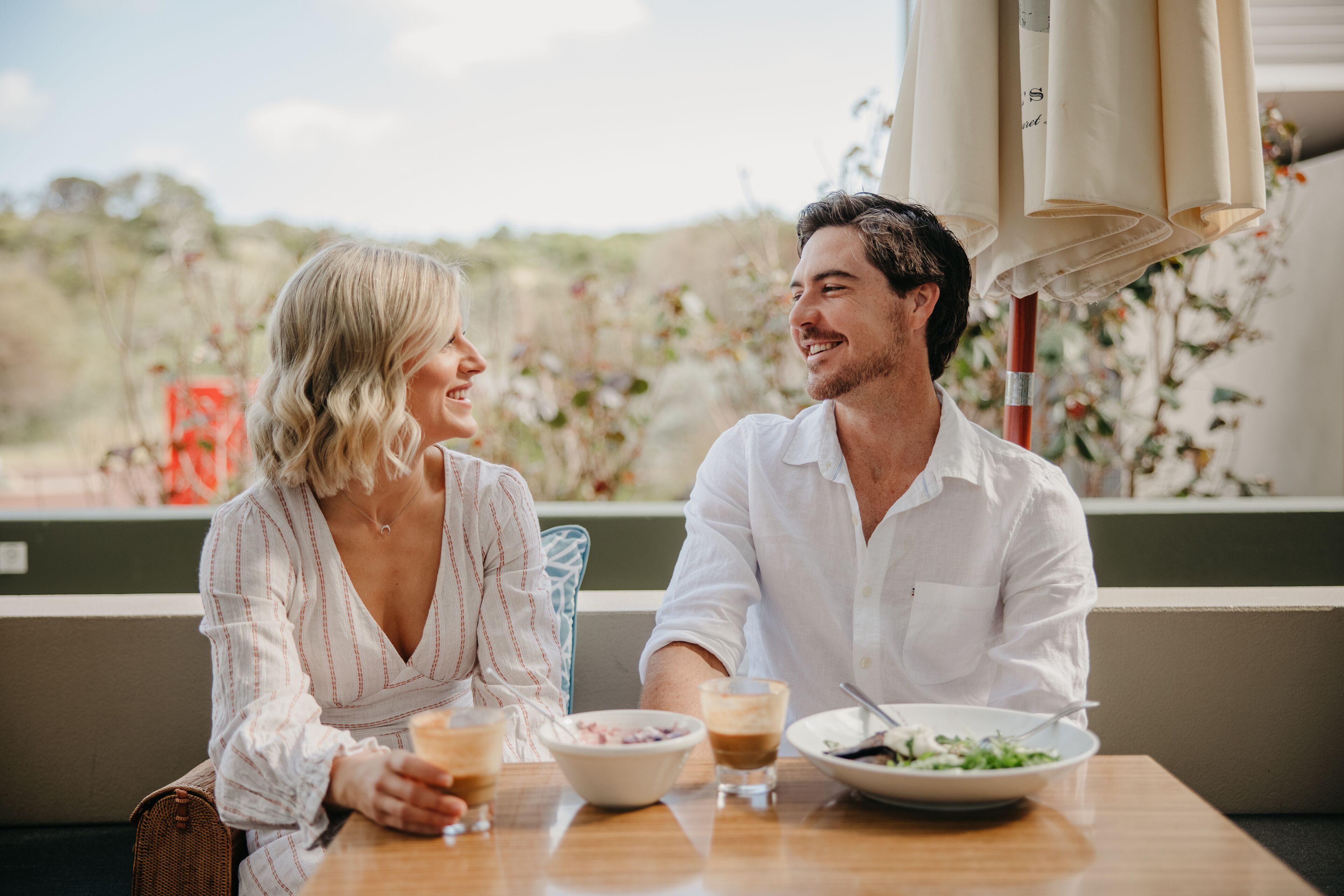 Um casal jantando em mesa externa com vista para a paisagem.