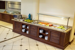 Uma mesa de buffet com diversos alimentos e acompanhamentos.