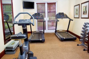 Uma academia com esteiras, bicicleta ergométrica e um banco de musculação.
