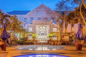 Um hotel com uma piscina grande, área de estar ao ar livre e uma entrada imponente.