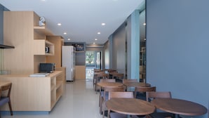 Restaurante moderno com mobiliário de madeira, balcão e vista para o exterior.