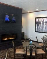 Quarto com lareira, televisão na parede, uma pintura e área de refeições com cadeiras e mesa.