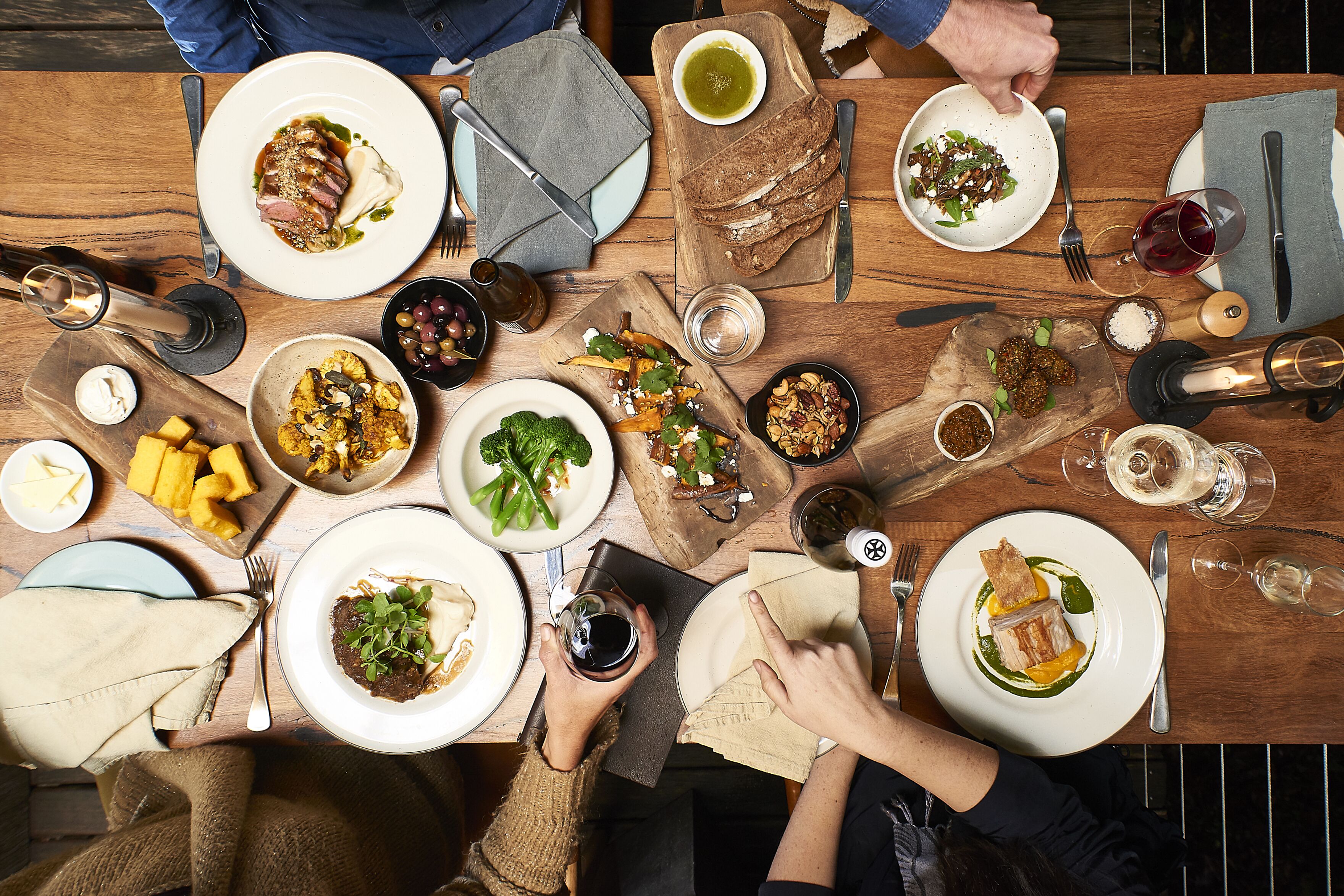 Uma mesa de jantar com diversos pratos e bebidas, indicando um ambiente de restaurante.