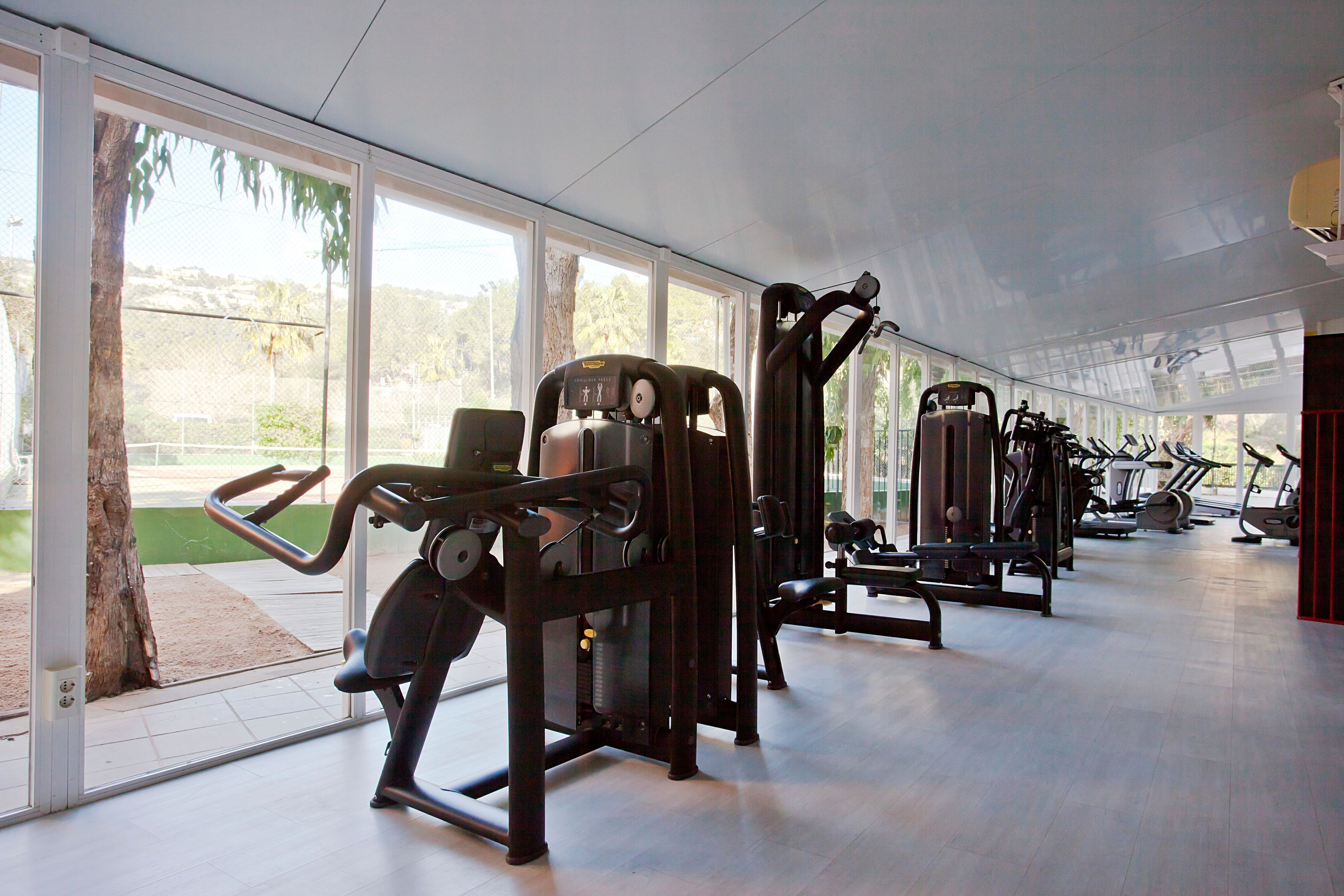 Uma academia com equipamentos de exercício, janelas amplas e vista para o exterior.
