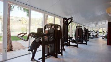 Uma academia com equipamentos de exercício, janelas amplas e vista para o exterior.
