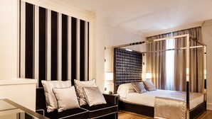 Um quarto moderno com parede listrada em preto e branco, uma cama com cabeceira e um sofá com almofadas.