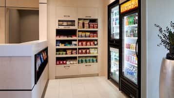 Um supermercado com prateleiras cheias de petiscos e bebidas, uma área refrigerada e um balcão de atendimento.