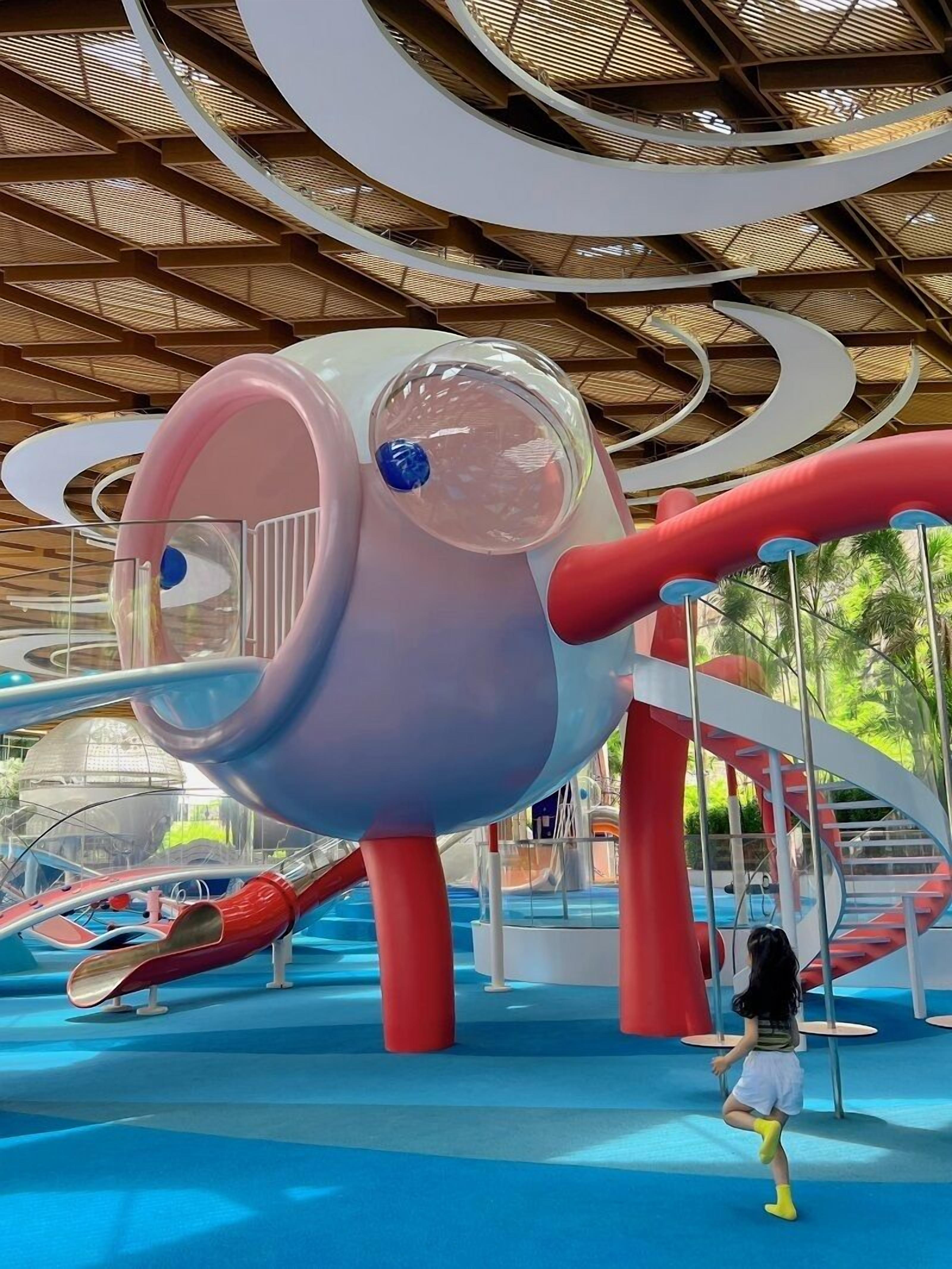 Um espaço de recreação infantil moderno, com uma grande estrutura de escorregador colorido e uma escada em espiral.
