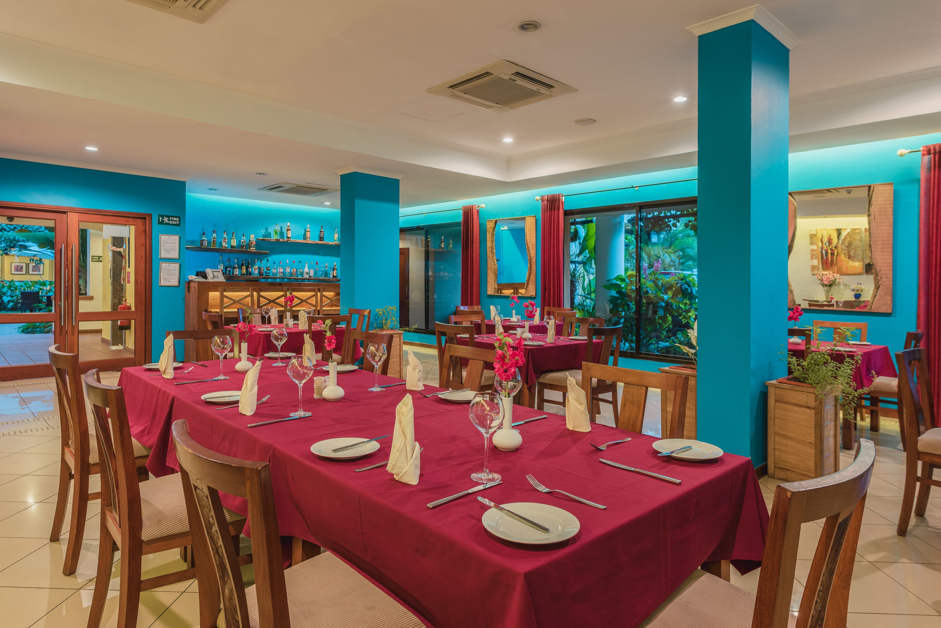 Restaurante com mesas preparadas para refeições, área de bar e vista para o exterior.