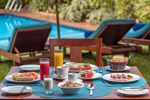 Uma mesa de café da manhã com pratos de comida, um copo de suco de laranja e uma tigela de cereal.