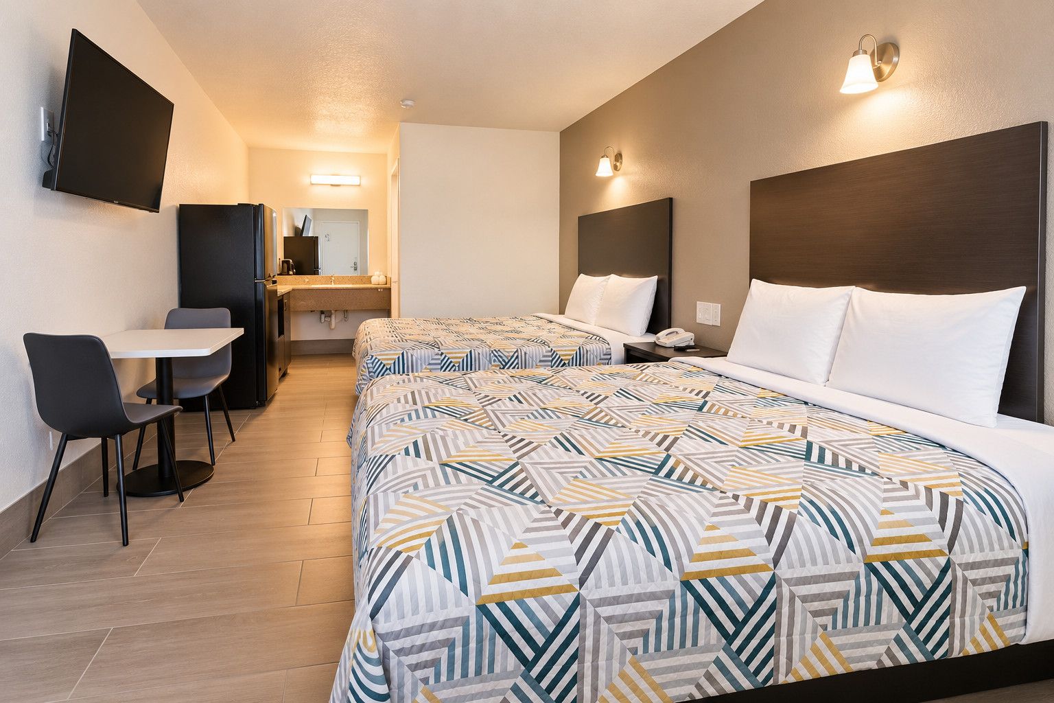 Quarto de hotel com duas camas, uma escrivaninha e uma cadeira.