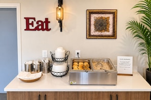 Disposição de buffet de café da manhã, com pratos, talheres e uma placa.