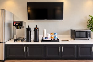Uma cozinha compacta equipada com cafeteira, micro-ondas e frigorífico.