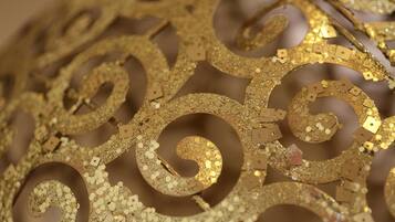 Um detalhe de uma estrutura dourada decorativa com padrões intrincados e pequenos detalhes refletivos.