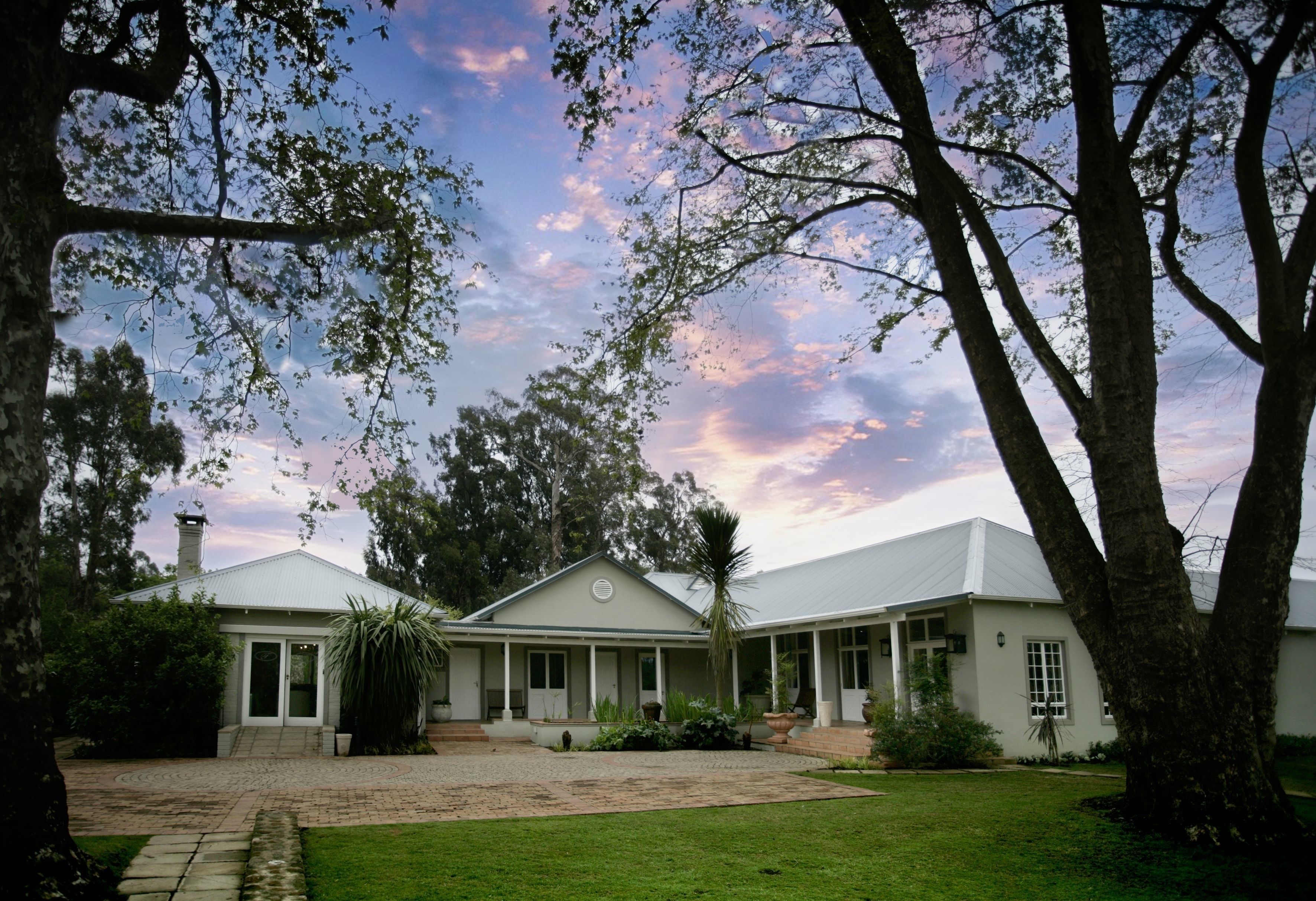 Uma casa de dois andares com varanda coberta, entrada de tijolos e gramado bem cuidado.