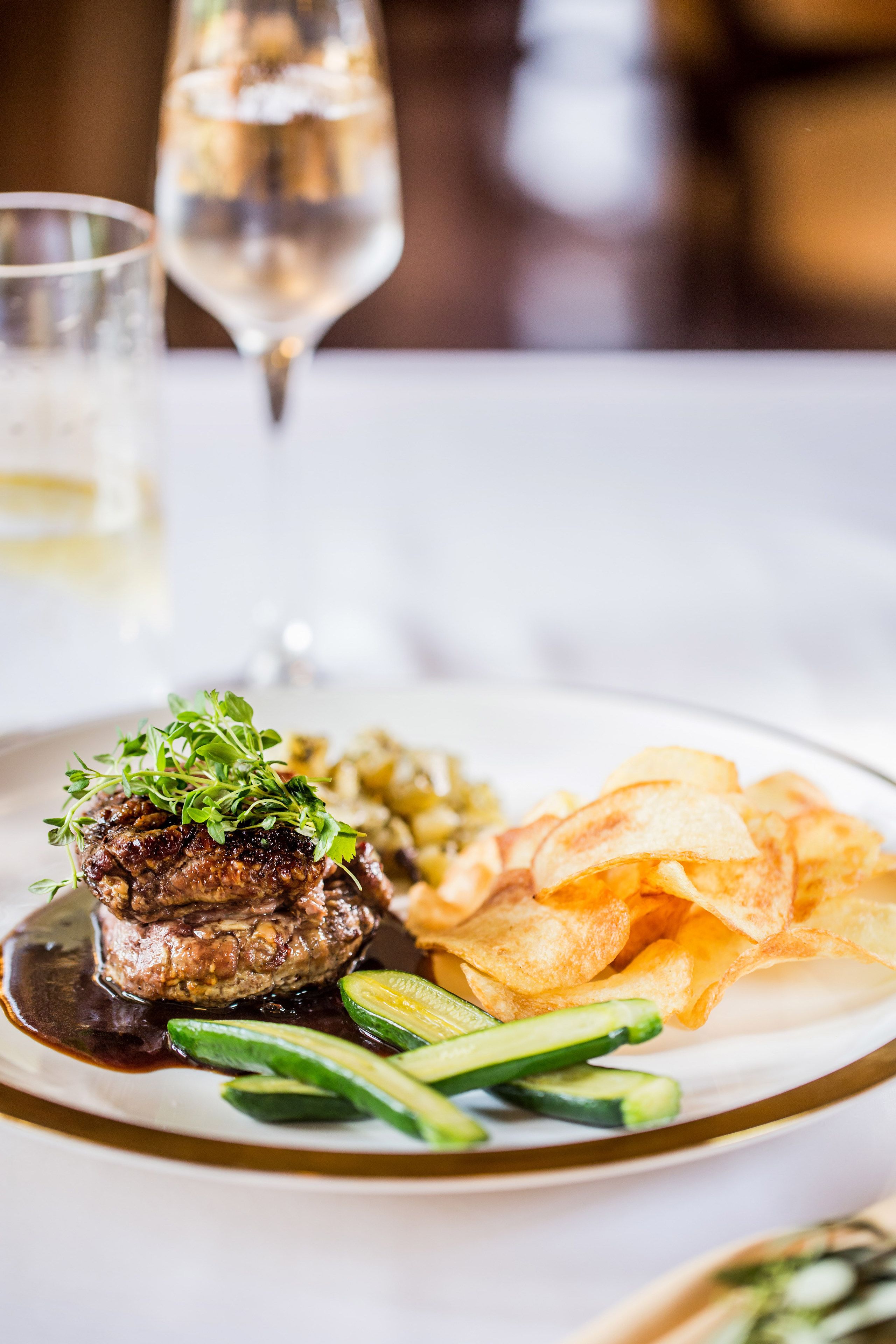 Prato de comida com bife, batatas fritas e legumes.
