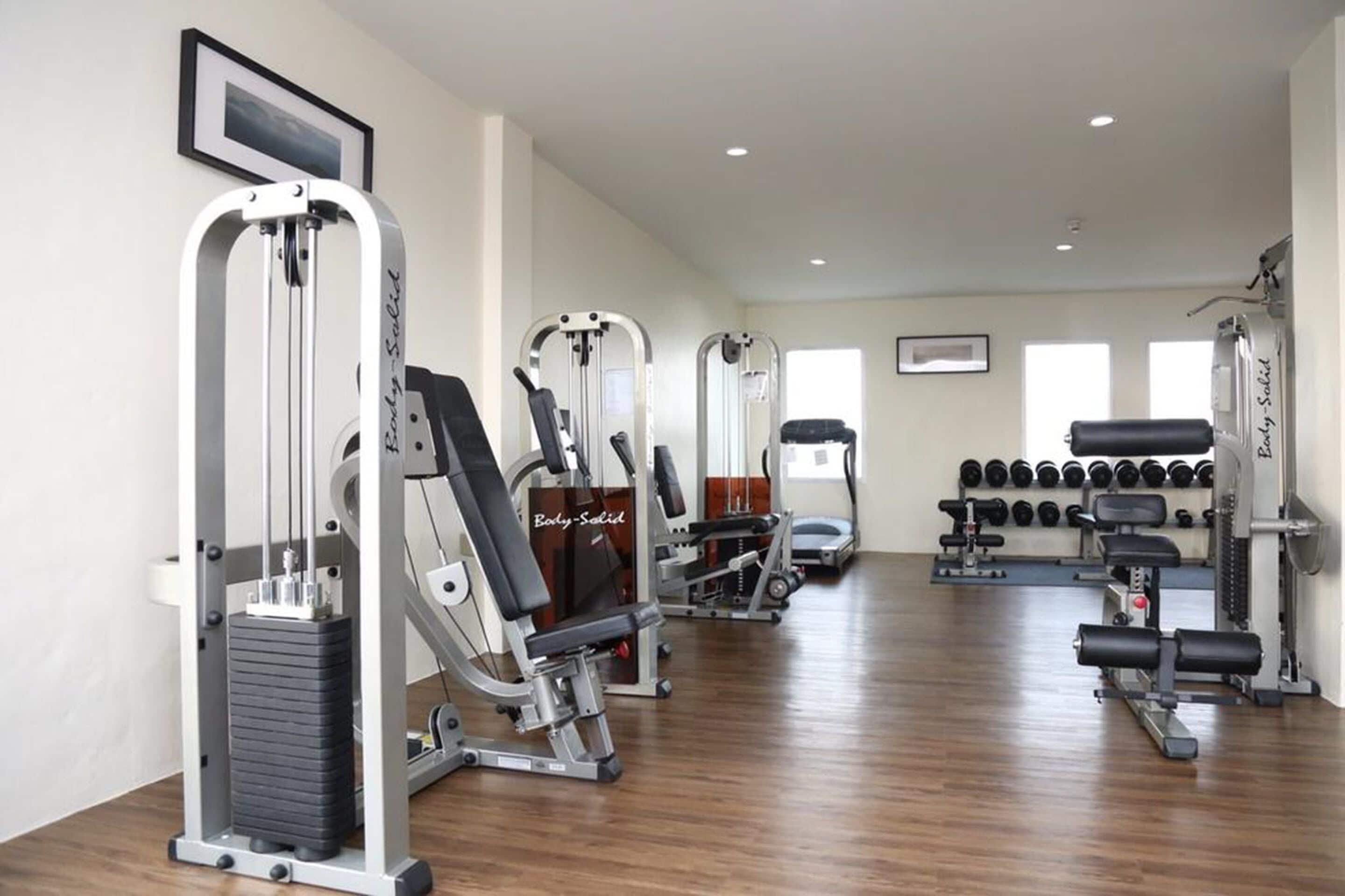 Uma academia com diversos equipamentos de exercício, halteres e um banco.