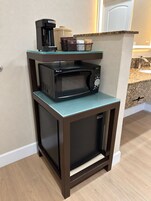 Cozinha compacta com micro-ondas e cafeteira em uma bancada pequena.