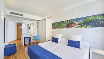 Quarto de hotel moderno com uma cama grande, uma escrivaninha, uma cadeira e uma pequena cozinha.