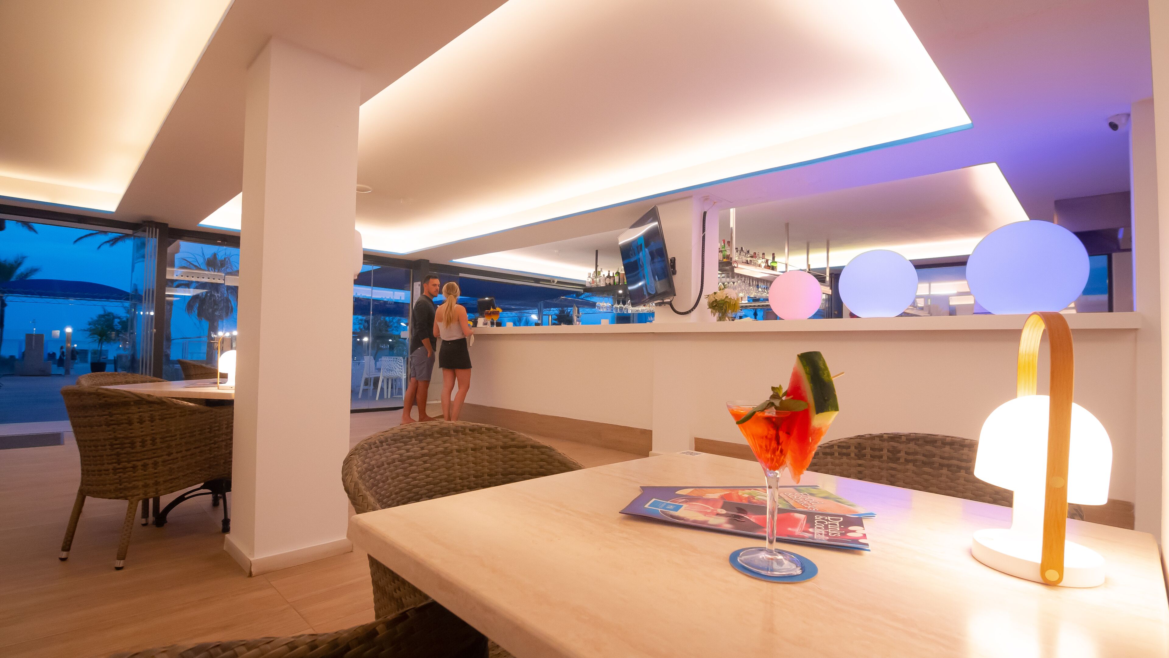 Uma área de bar moderna com balcão, assentos e vista para o exterior.