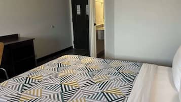 Quarto de hotel com cama, escrivaninha e cadeira.