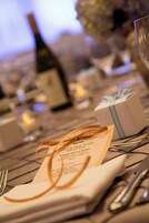 Uma mesa posta com um menu, uma garrafa de vinho e uma caixa de presente.