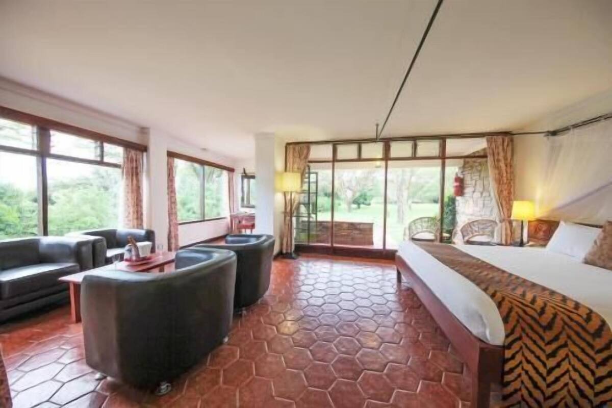 Um quarto com sofá, poltrona, mesa e cama.