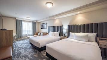 Quarto de hotel com duas camas, uma escrivaninha e uma cadeira.