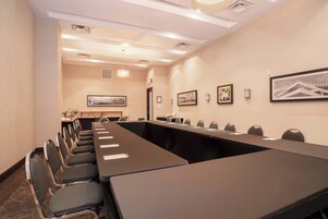 Uma sala de conferências com uma mesa comprida, cadeiras e obras de arte emolduradas nas paredes.