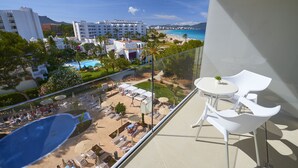 Varanda de resort com piscina, cadeiras de descanso e vista para a praia e o oceano.