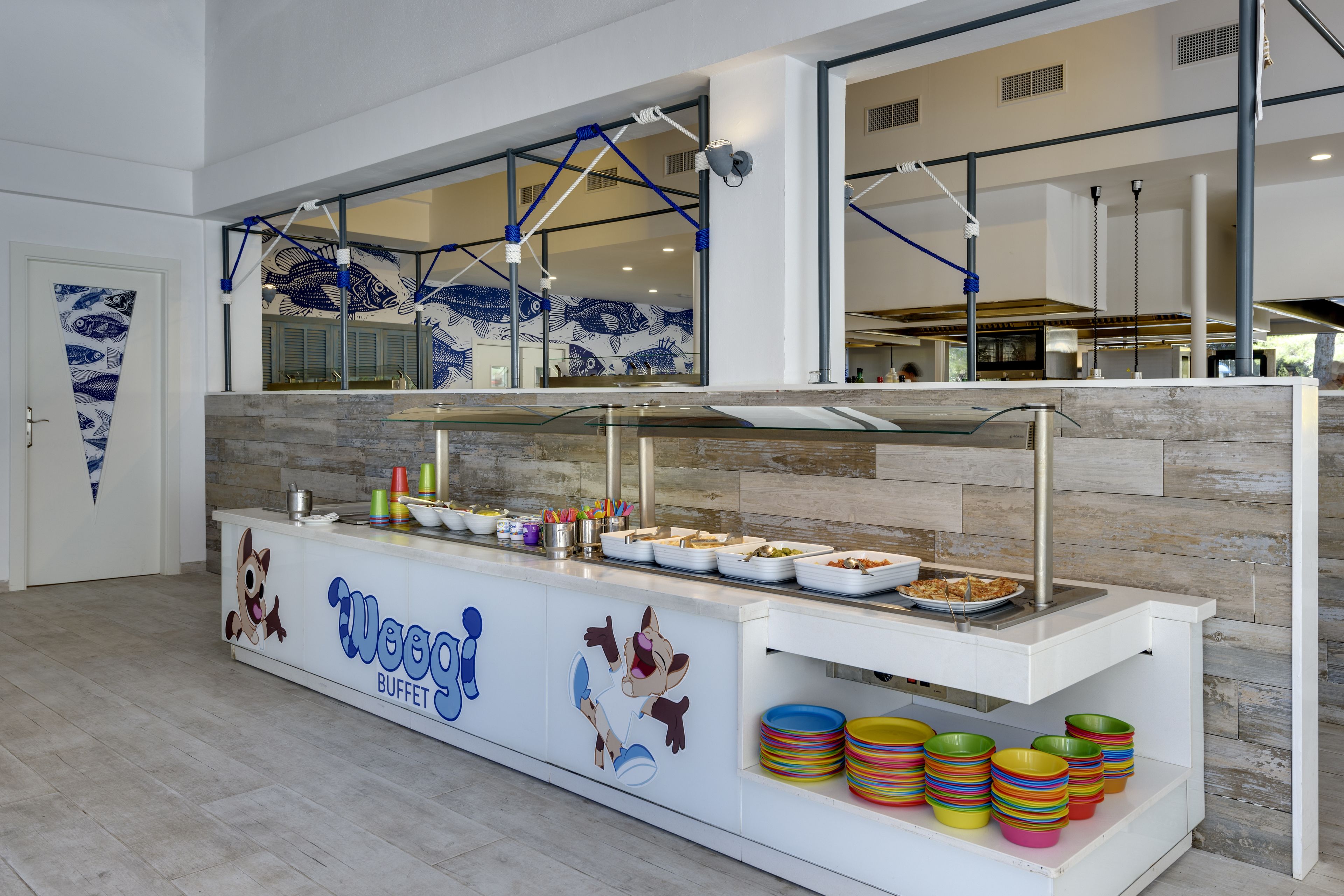 Uma área de buffet com um balcão branco, tigelas coloridas e um design com tema de cachorro.