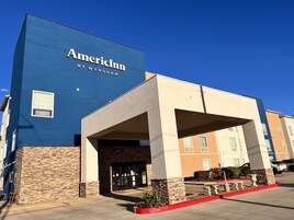 Um hotel com fachada azul marcante e área de entrada coberta.