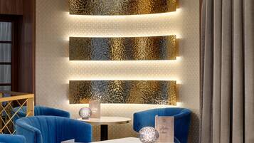 Um hall moderno com assentos azuis, um lustre e painéis decorativos na parede.