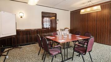 Sala de conferência com uma mesa grande, seis cadeiras, um quadro branco e parede de painel de madeira.